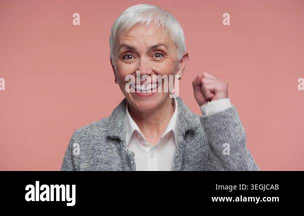 Portrait of a happy mature woman smiling and raising her fist in ...