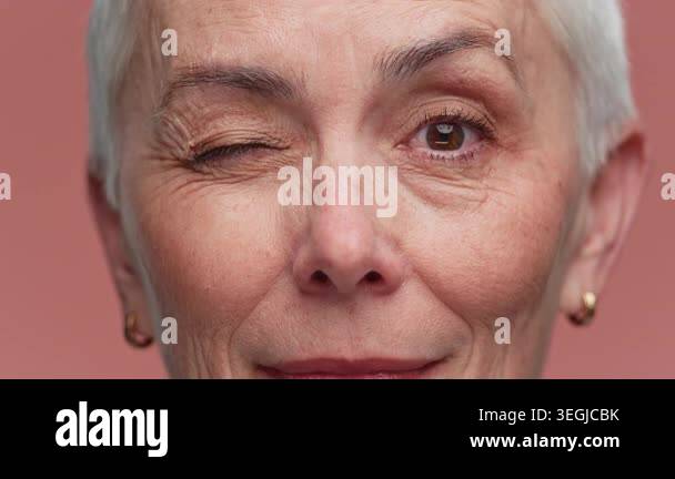 Close up portrait of an older woman with short gray hair winking with a ...