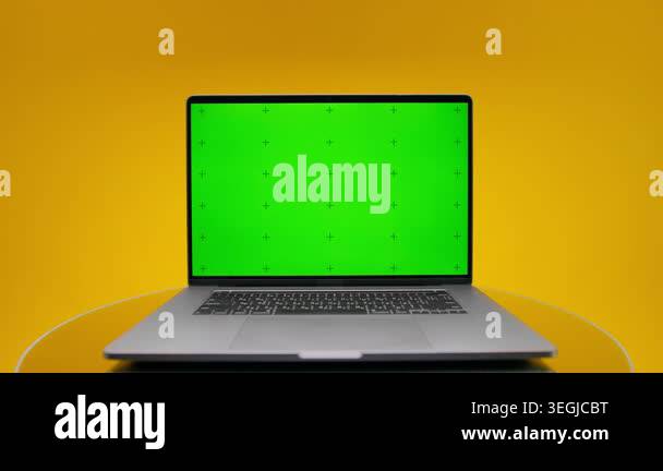 Open laptop with green screen display on reflective table against a ...