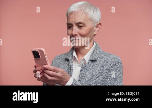 Older woman with short gray hair smiles while typing a message on her ...