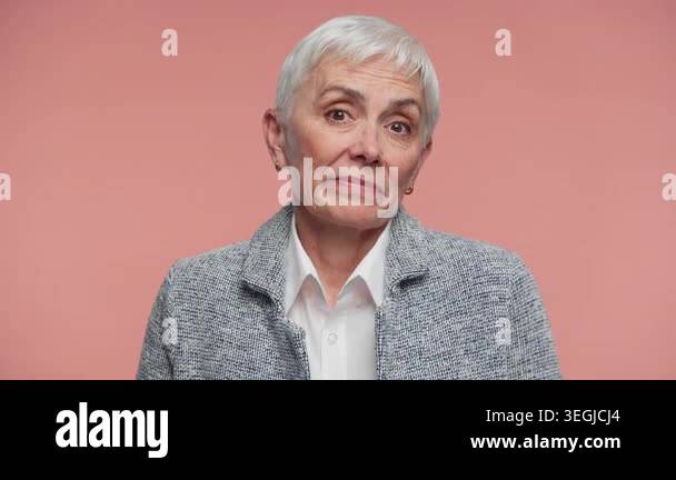 Older woman with short gray hair gives a shoulder shrug and uncertain ...