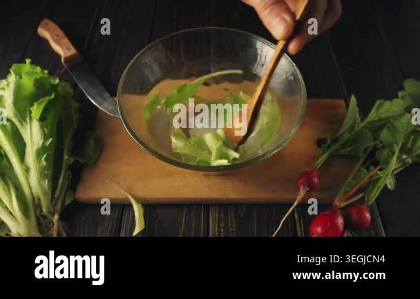 Hand stirring fresh lettuce leaves in a clear bowl filled with water ...