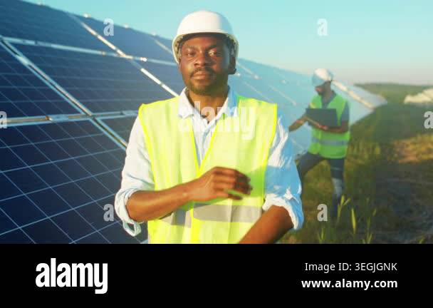 engineer portrait with solar panels in background, arms crossed and ...