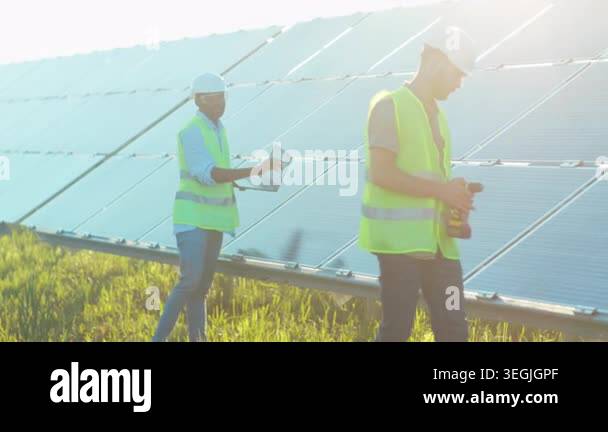 white and black technicians maintain solar panels during golden hour ...