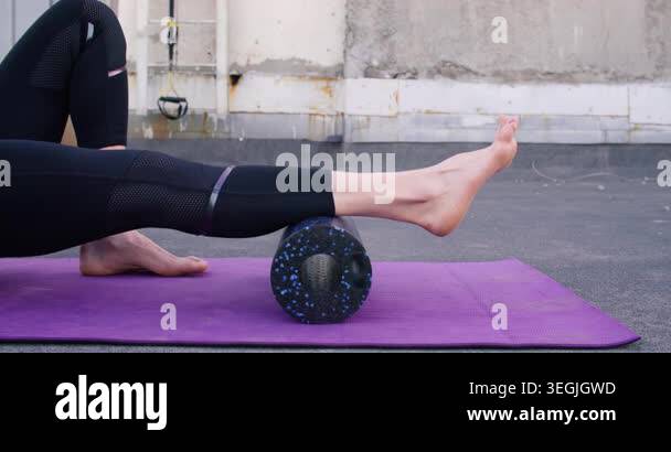 Fitness workout. Foam rolling calves. Flexible female legs performing ...