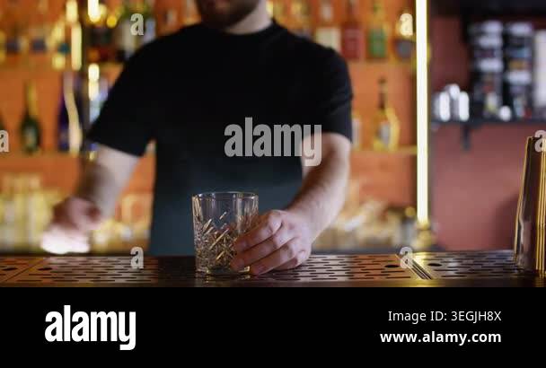 Ice glass. Cocktail making. Professional male bartender using cold cube ...