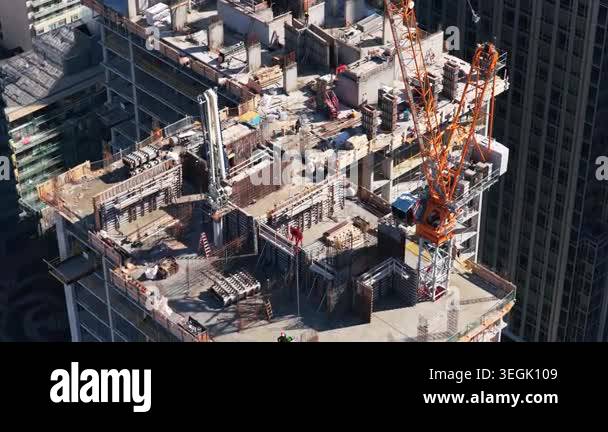 Construction workers and crane building skyscraper in downtown area ...