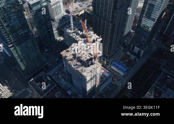 High rise building construction in downtown area with cranes lifting ...