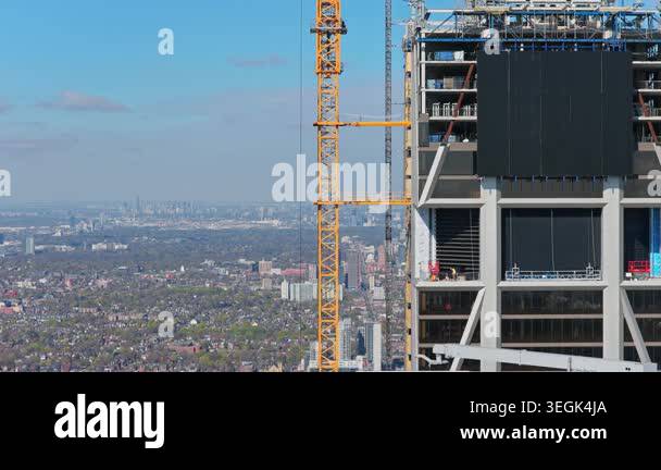 Yellow construction crane moving on skyscraper building site with ...