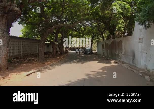 Ghana street scene with local people walking on asphalt road shaded by ...