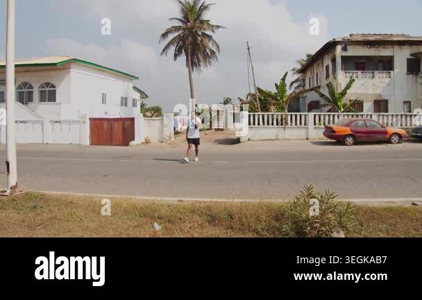 African American man with tattoos and beard walking along an asphalt ...