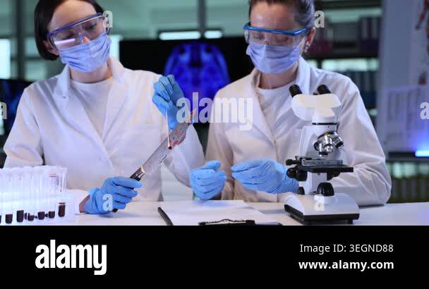 Women forensic scientists take blood sample from knife with swab in lab ...