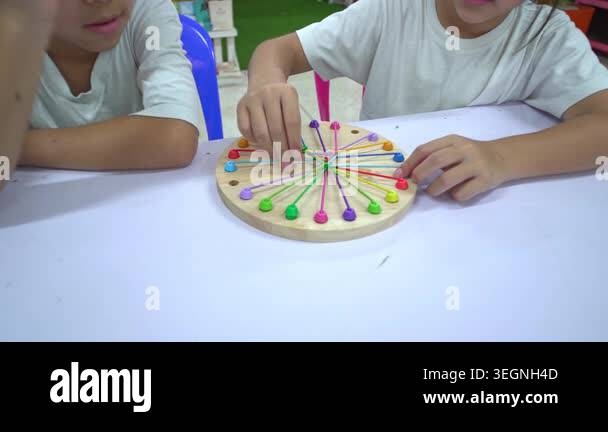 Close up of children's hands playing with a colorful wooden stringing ...