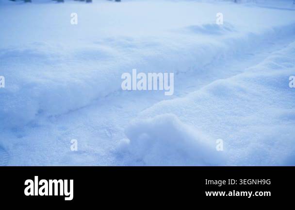 Fresh white snow covering ground in winter close up with blue tones ...