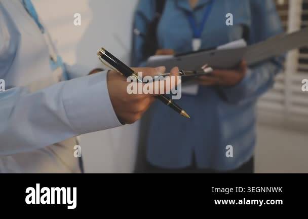 close up of doctor hand holding pen and writing on clipboard at ...