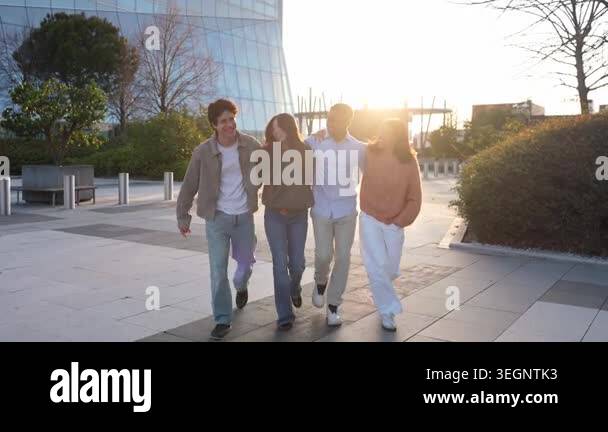 Slow motion of four multi ethnic friends walking together arm in arm ...