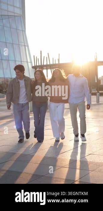 Multiracial group of young friends having fun walking arm in arm in a ...