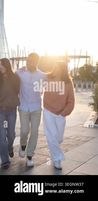 Group of three happy multiethnic friends walking together arm in arm ...