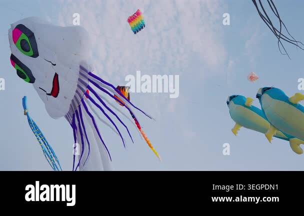 Colorful kite festival with giant inflatable kites flying in blue sky ...