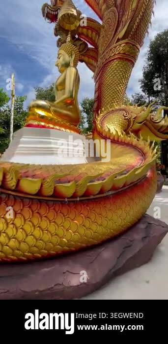 Close-up cinematic view of a golden Buddha statue and giant Naga ...