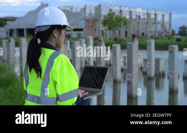 Woman wearing safety gear using laptop on a construction site near ...