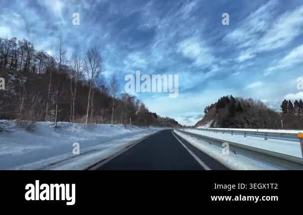 POV driving footage on a winter mountain highway surrounded by snow ...