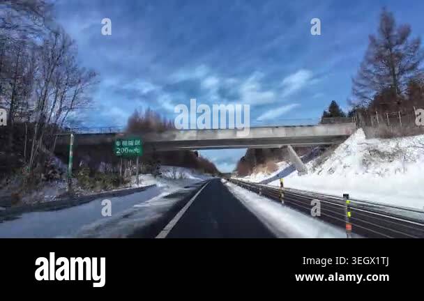 POV driving footage on a winter highway passing under a bridge with ...