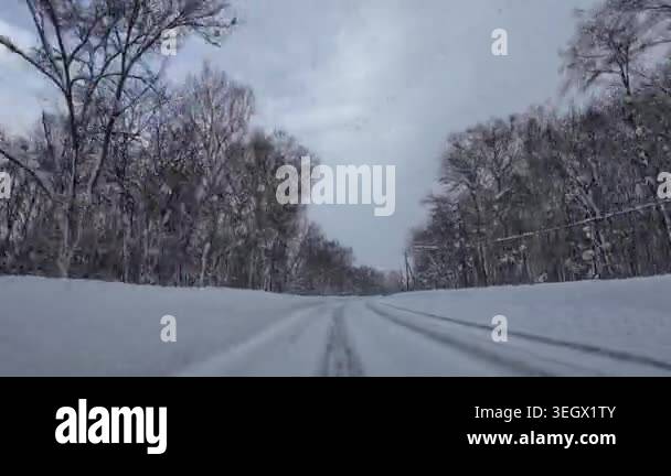 POV driving footage on a snow-covered winter highway passing beneath a ...