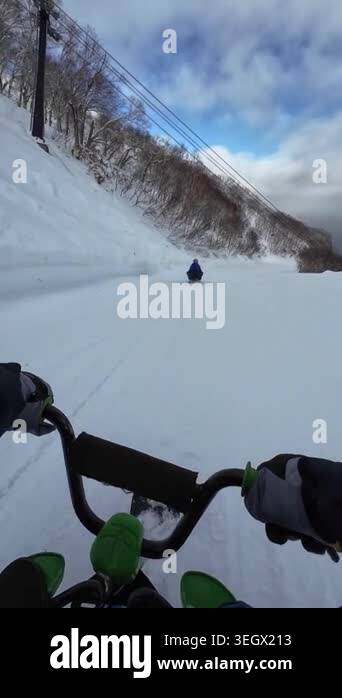 First person POV riding a snow kart downhill on a snow covered mountain ...