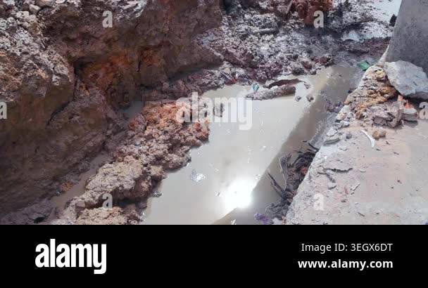 Close up of an excavator bucket digging into wet, muddy earth within a ...