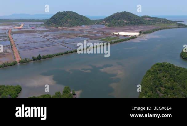 Forward aerial view of coastal salt pans and a river near small hills ...