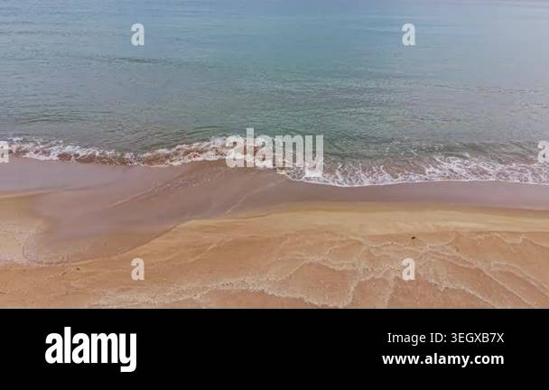 Soft waves are coming onto the sandy beach. The water is clear and the ...