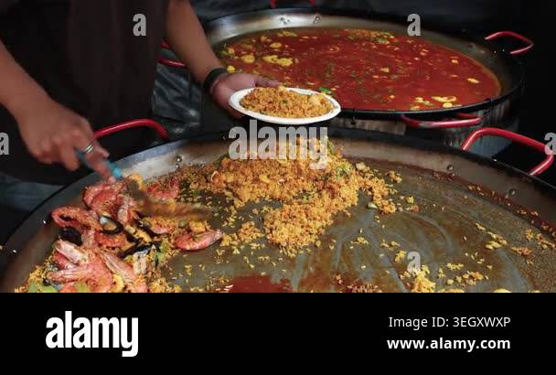Street food vendor serves fresh seafood paella from large traditional ...