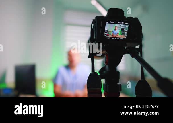 Professional camera on tripod with a man on the display. Medic creates ...