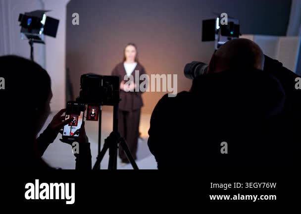 Assistant using smartphone to film woman during video production ...