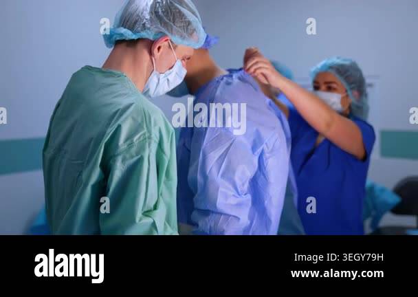 Medical staff helping the surgeon to get dressed for the surgery ...
