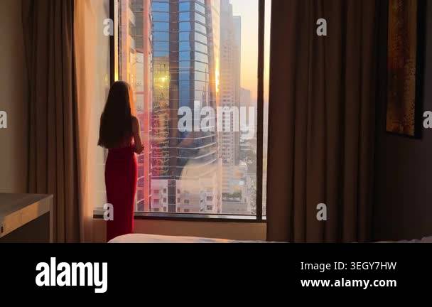 woman in red dress looking out from hotel window, travel video frame ...