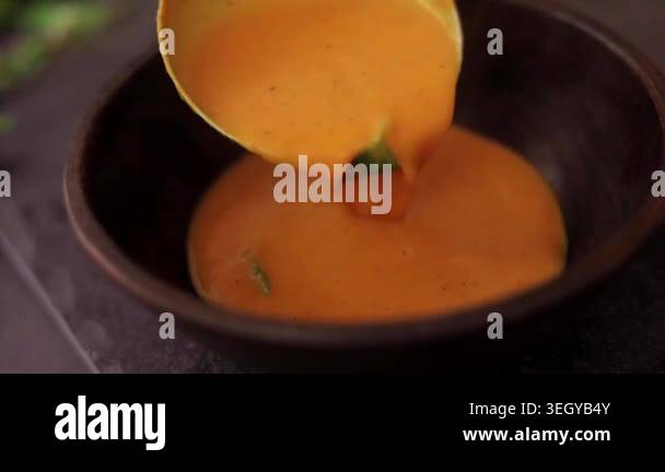Creamy tomato soup with spicy flavor and fresh basil garnish served hot ...
