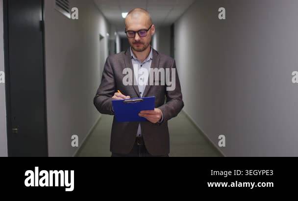 Concentrated man in glasses stands in lobby and records inspection ...