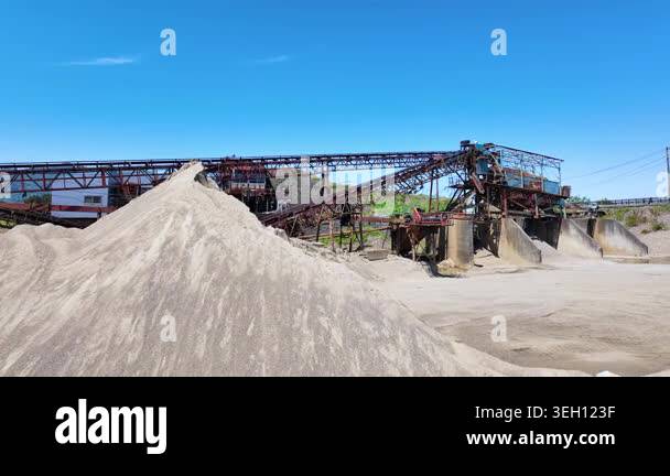 Panning shot of a sand pile at a quarry plant with large transport ...
