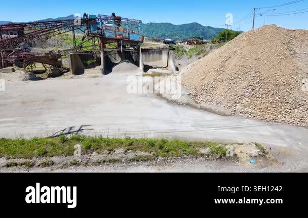Panning shot of a gravel pile at a quarry plant with large transport ...