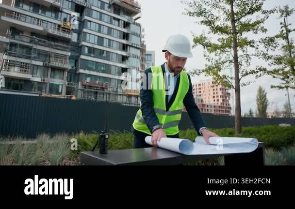 Caucasian man builder engineer in helmet looking plan blueprint ...