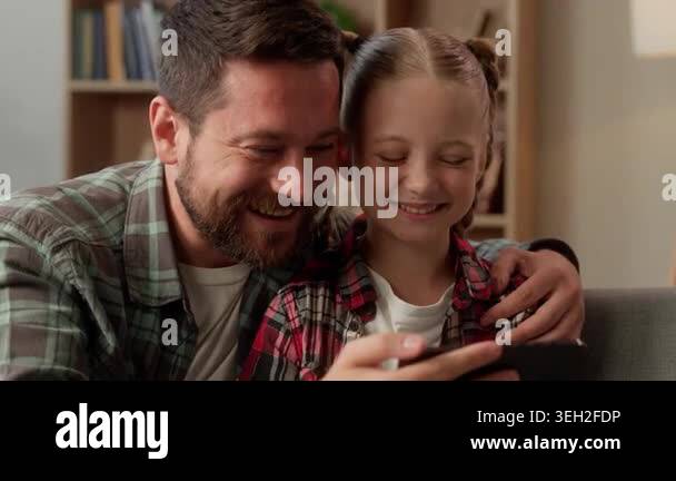 Laughing Caucasian family male dad hug little girl daughter watching ...