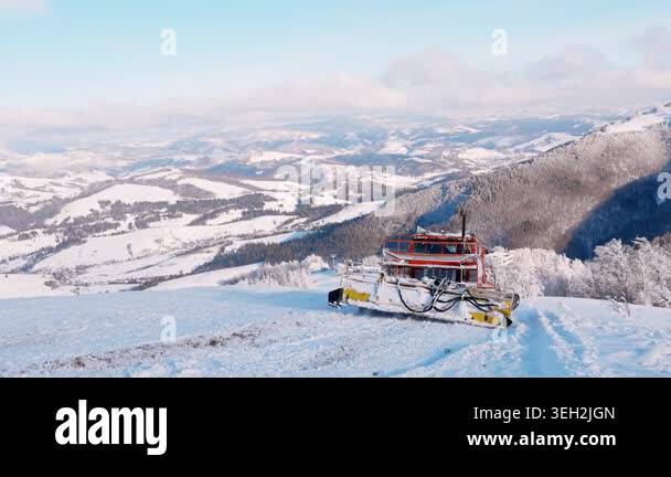 Back view of red snowplow removing fresh snow down hill. Panoramic view ...
