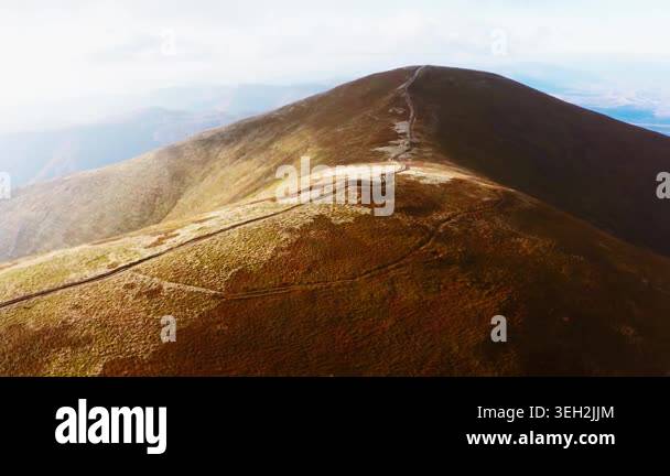 Narrow pathways among meadows on high mountain ridge under white clouds ...