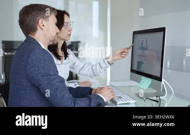 Two business colleagues working together on a computer, pointing at ...