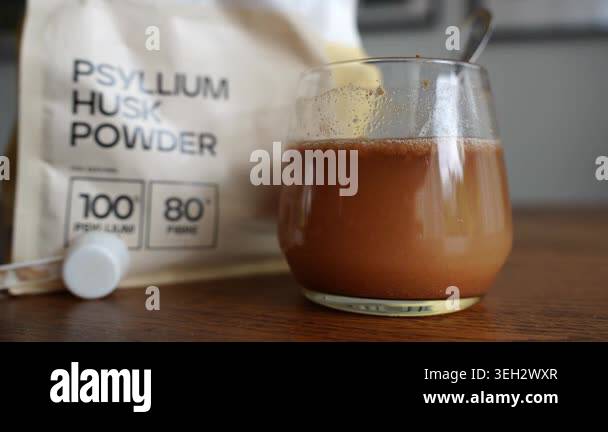 Psyllium husk powder being stirred into a glass of water with the ...