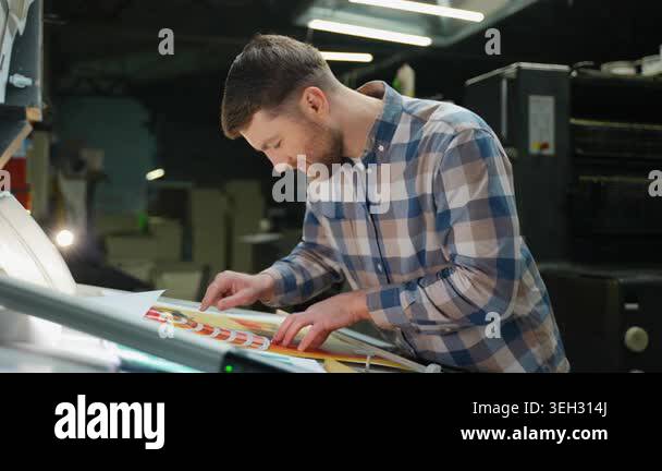 Professional print worker controlling the quality and color of a ...