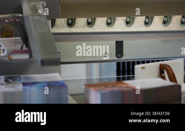 Male workers hands aligning a stack of printed paper in a large ...