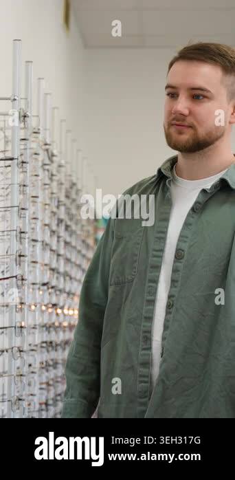Smiling young man with a beard choosing and trying on new stylish ...